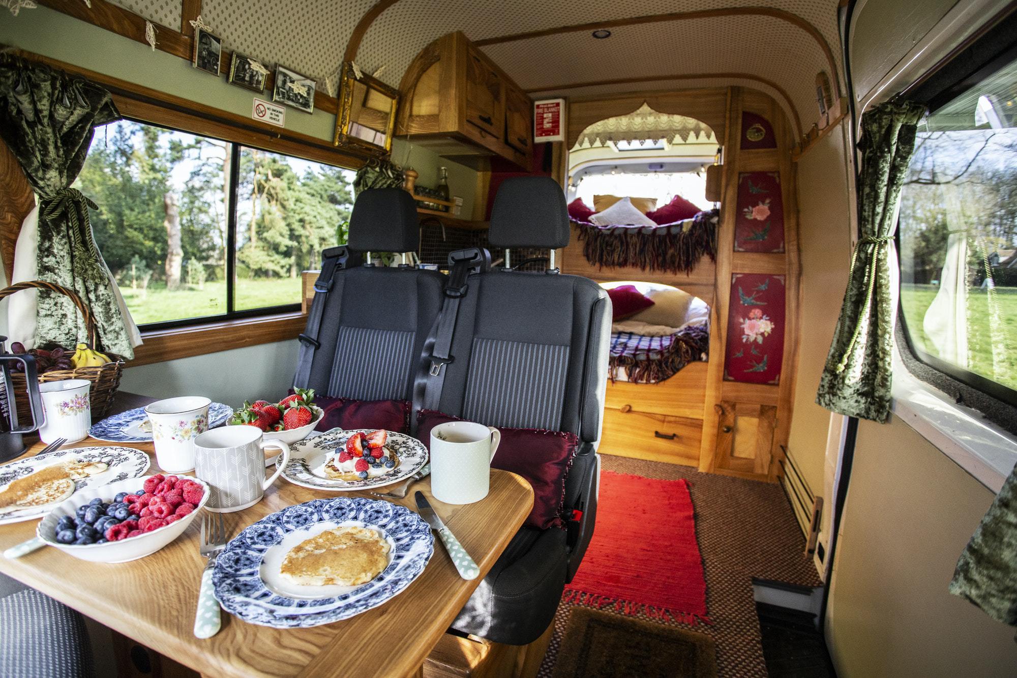 Interior view of camper van with breakfast on table. - modhop.com